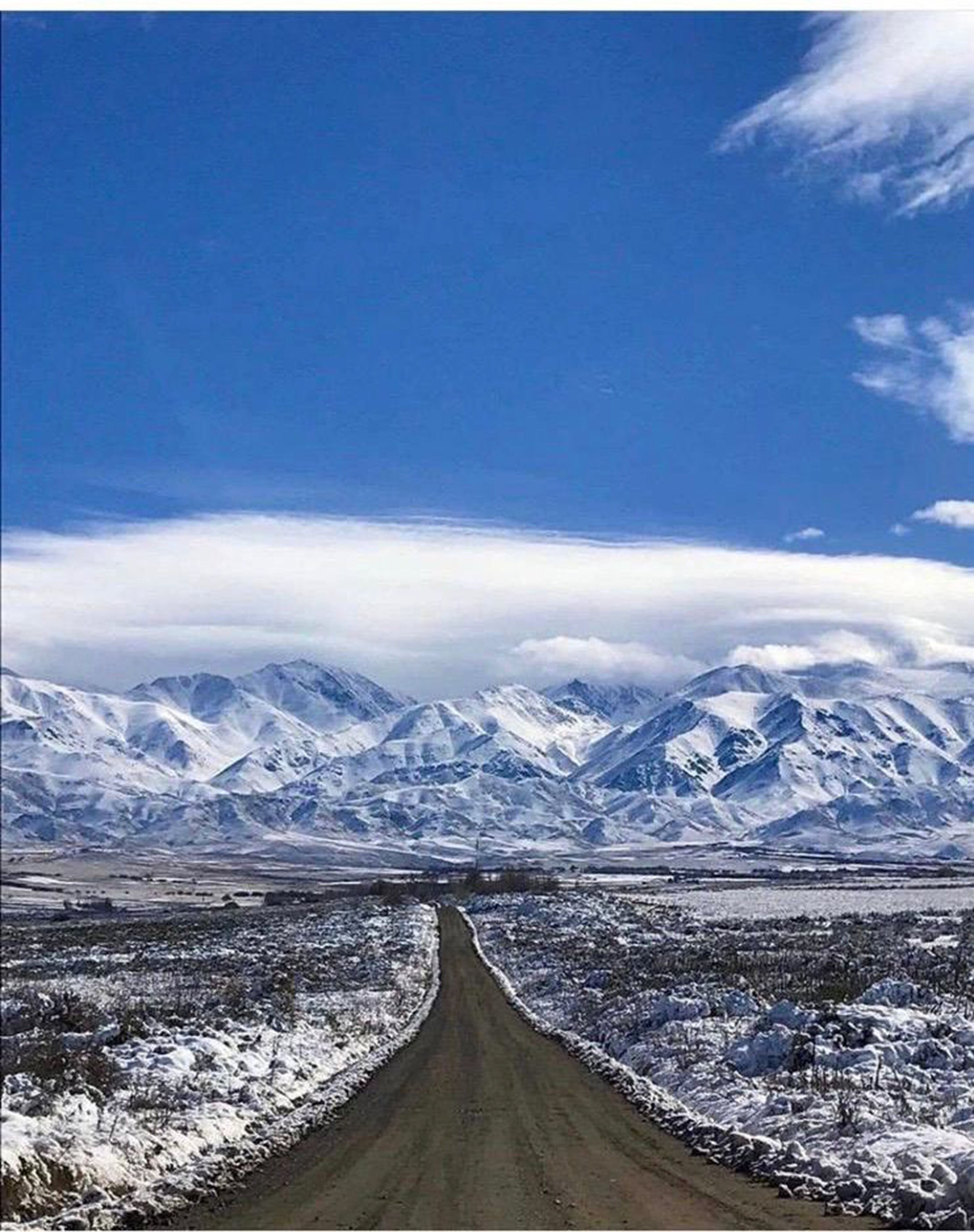 Uma estrada coberta de neve que leva a uma paisagem montanhosa.