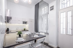 Uma cozinha moderna com armários brancos, micro-ondas e uma área de refeições com mesa posta para quatro pessoas.
