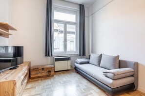 Uma sala de estar moderna com um sofá, uma televisão, uma mesa de centro de madeira e uma janela com cortinas.