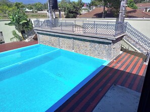 Piscina com parede de pedra e guarda-corpo de metal.