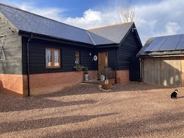 Uma casa com telhado inclinado, alicerce de tijolos e entrada com calçamento de brita.