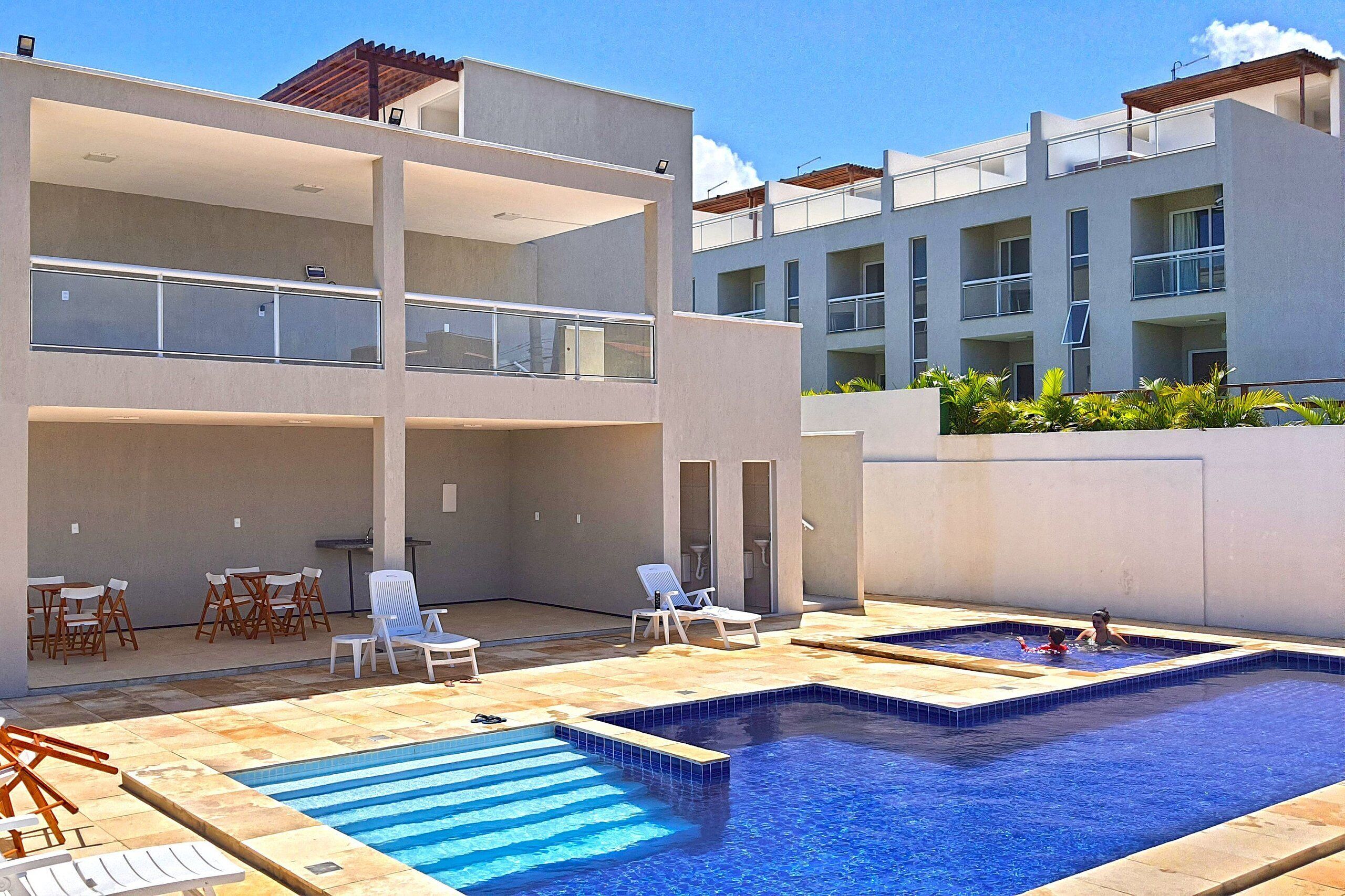 Um hotel moderno com piscina no terraço, área de estar externa e edifício de vários andares.