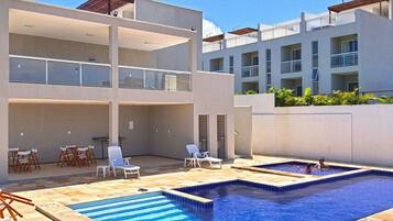 Um hotel moderno com piscina no terraço, área de estar externa e edifício de vários andares.