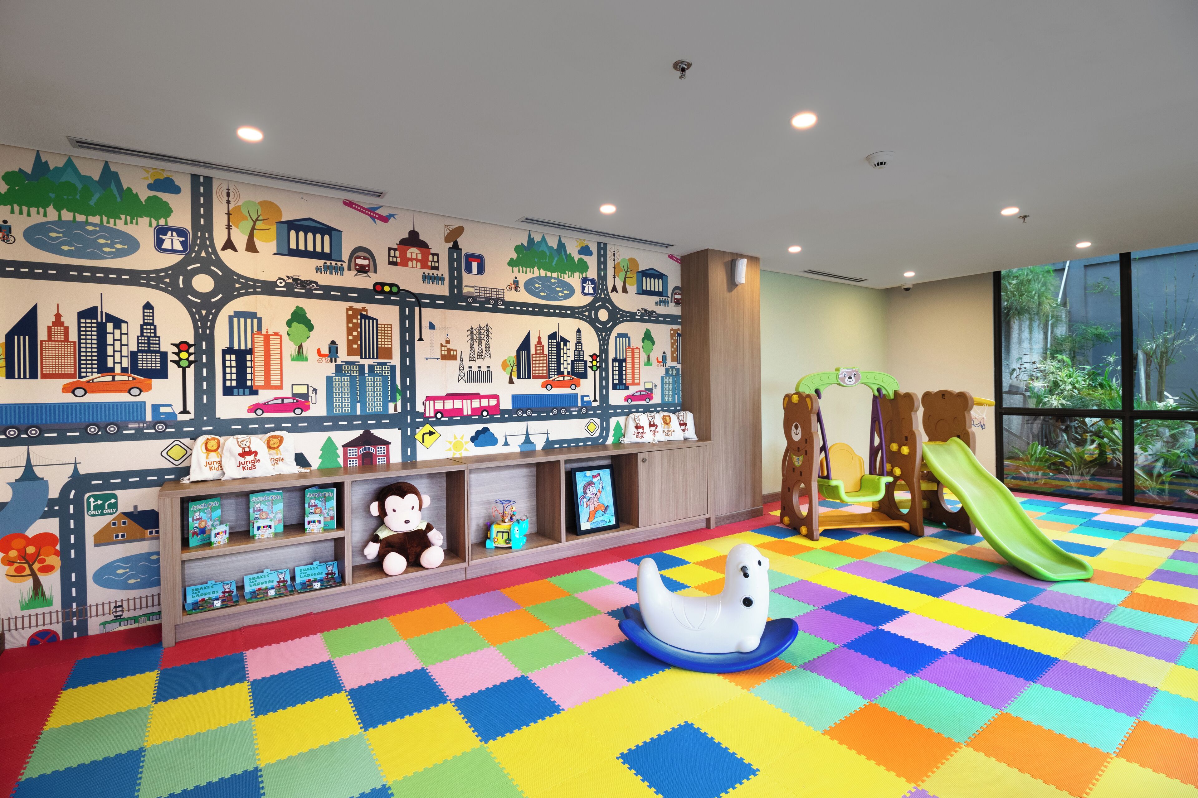 Espaço infantil com piso colorido, um escorrega e decorações educativas nas paredes.