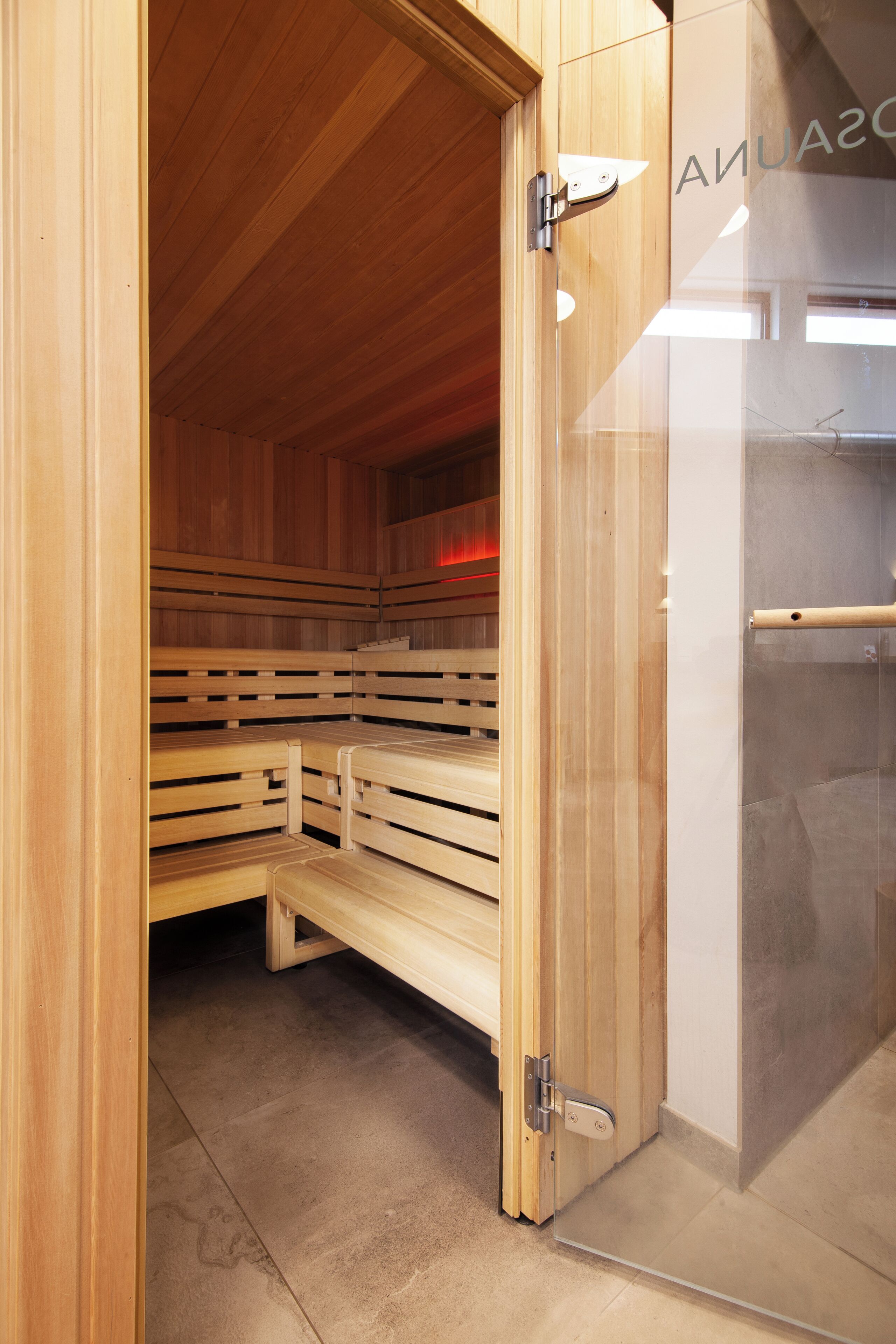 Uma sauna com bancos de madeira e porta de vidro.