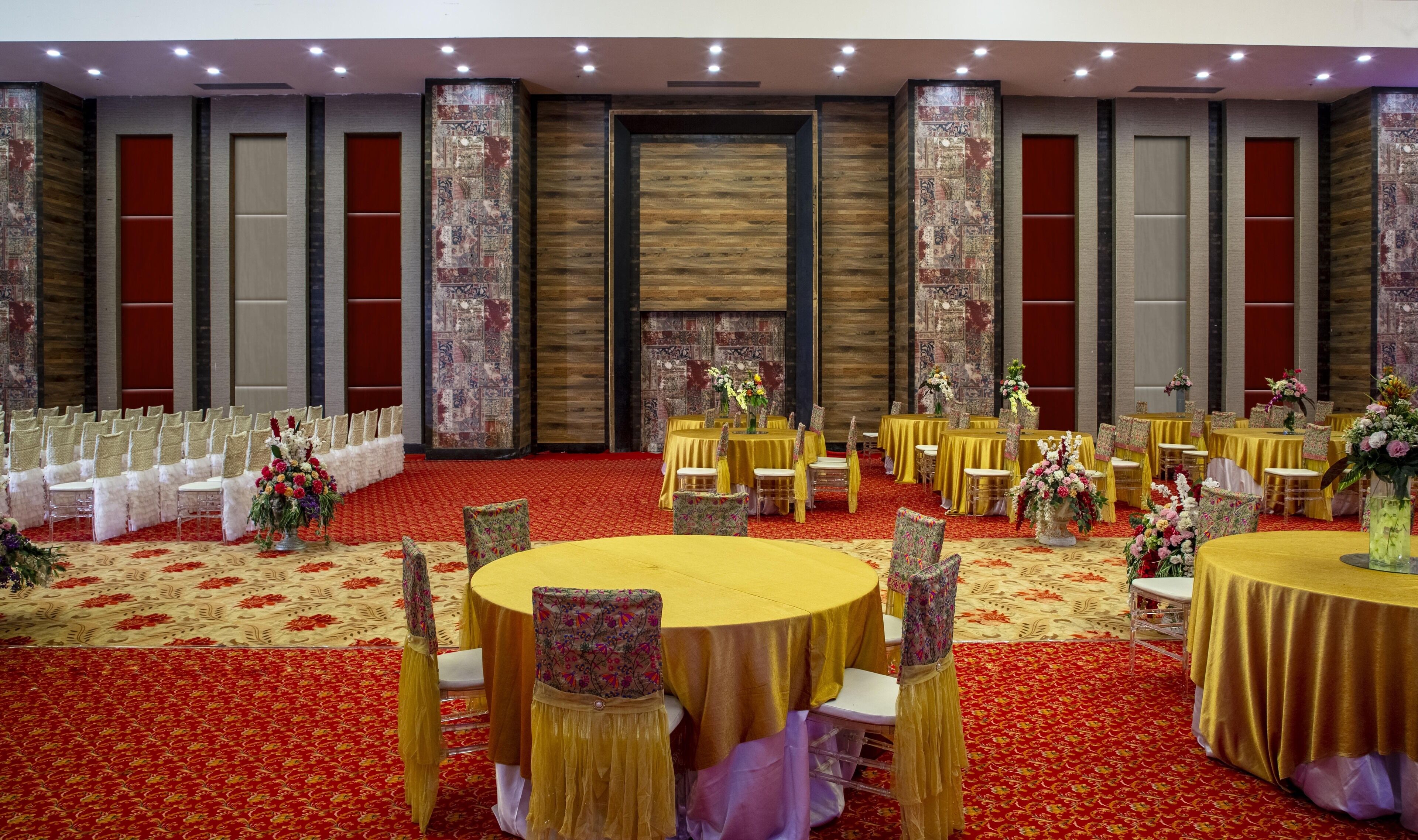 Uma sala de banquetes com mesas redondas, cadeiras e um tapete vermelho.
