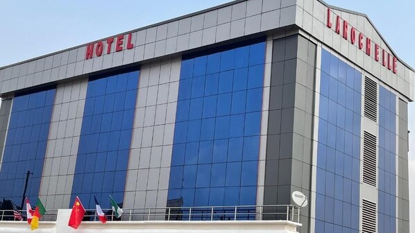 Um edifício de hotel moderno com fachada de vidro ampla e o nome "HOTEL LAROGCHEILLE" em destaque.