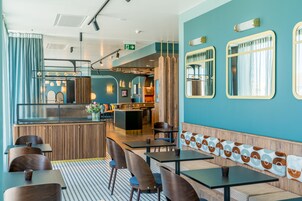 Interior de restaurante moderno, com área de bar, assentos e parede com padrão.