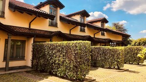 Uma fileira de edifícios amarelos com telhados vermelhos e molduras de janela pretas.