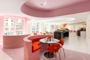 Um interior moderno com uma área de estar curva, uma mesa redonda central e uma cozinha ao fundo.