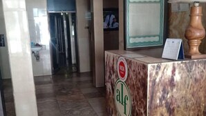 Uma receção com bancada de mármore, televisão na parede e uma lâmpada.
