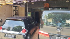Dois carros estacionados em frente a um edifício com telhado de metal e porta de vidro.