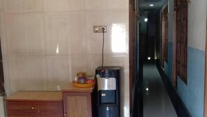 Um corredor com um dispensador de água, um armário de madeira e uma parede revestida de azulejos.