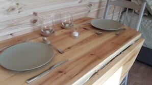 Uma mesa de jantar de madeira com um prato, faca, colher e três copos.