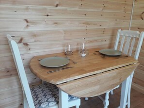 Uma mesa de jantar de madeira com dois pratos, talheres e copos.