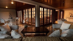 Uma sala de estar acolhedora com teto de madeira, uma mesa central e assentos confortáveis.