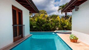 Piscina com vista para vegetação exuberante e um prédio com varanda.