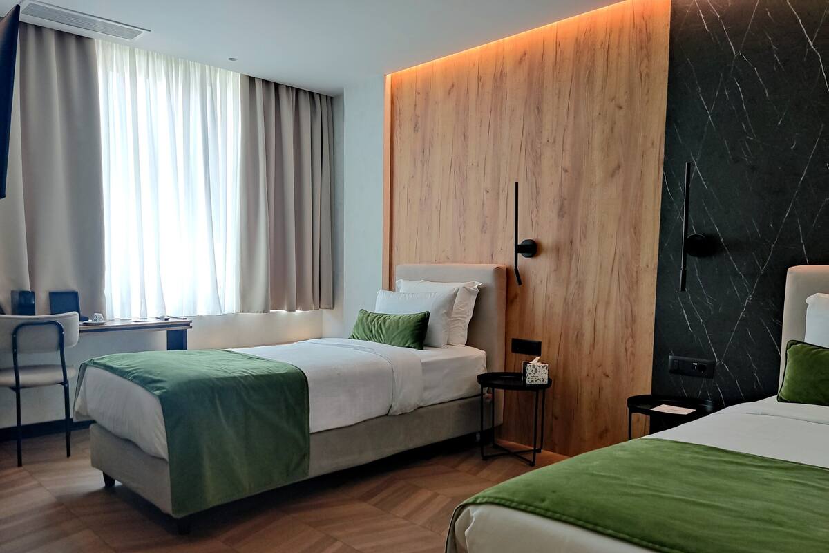 Quarto de hotel com cama, escrivaninha e cadeira.