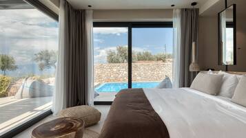 Quarto moderno com uma cama grande, vista para uma piscina e parede de pedra externa.