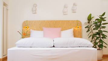 Uma cama bem arrumada com roupa de cama branca, uma cabeceira de madeira e duas luminárias de apoio.