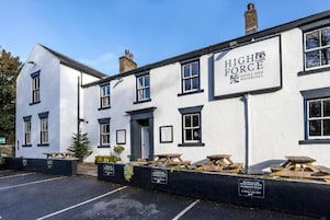 A white building with a sign reading "High Force Hotel and Waterfall".
