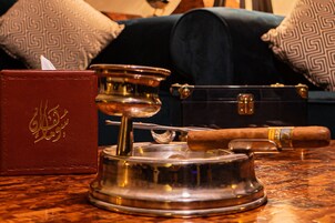 Um tradicional conjunto de narguilé, incluindo uma base de metal, um cachimbo e uma caixa vermelha com caligrafia árabe.