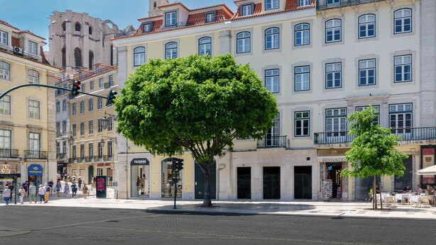 Rua arborizada com edifícios históricos, um café e uma loja chamada "TEZENIS".