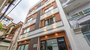 Um hotel com vários andares, varandas, janelas grandes e uma placa indicando ser uma residência de hóspedes.