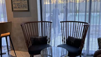 Um interior moderno com duas cadeiras curvas, uma mesinha redonda e um chão estampado.