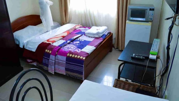 Quarto de hotel com uma cama, uma mesa de cabeceira com micro-ondas e um telefone.