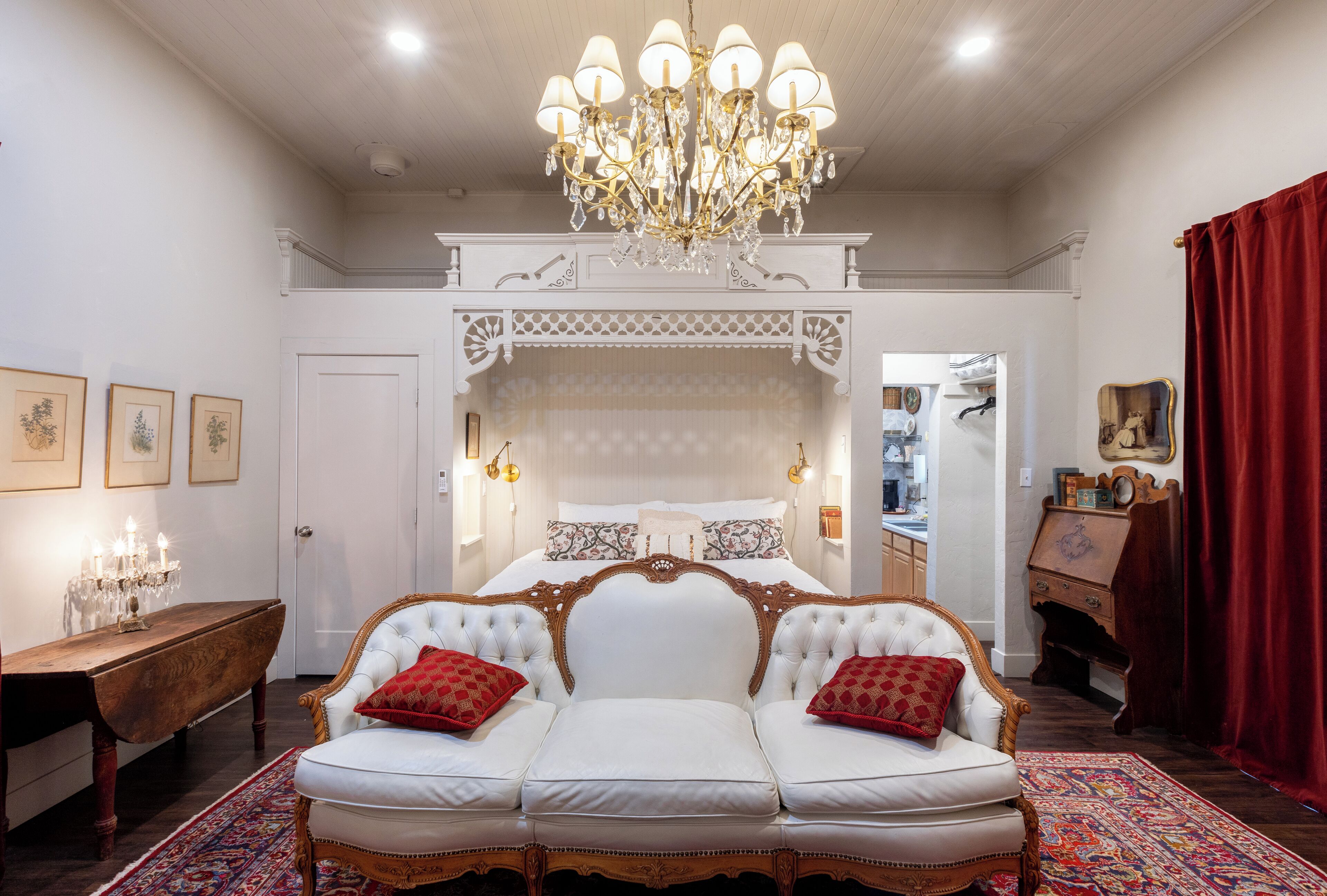 Um quarto luxuoso com uma cama grande, um lustre no teto ricamente decorado e uma cortina vermelha.