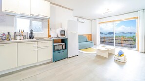 Cozinha moderna com vista para o mar, área de refeições com sofá azul e varanda com vista.