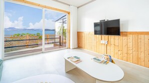 Quarto moderno com uma grande porta de correr de vidro que dá para uma varanda com vista para o mar.