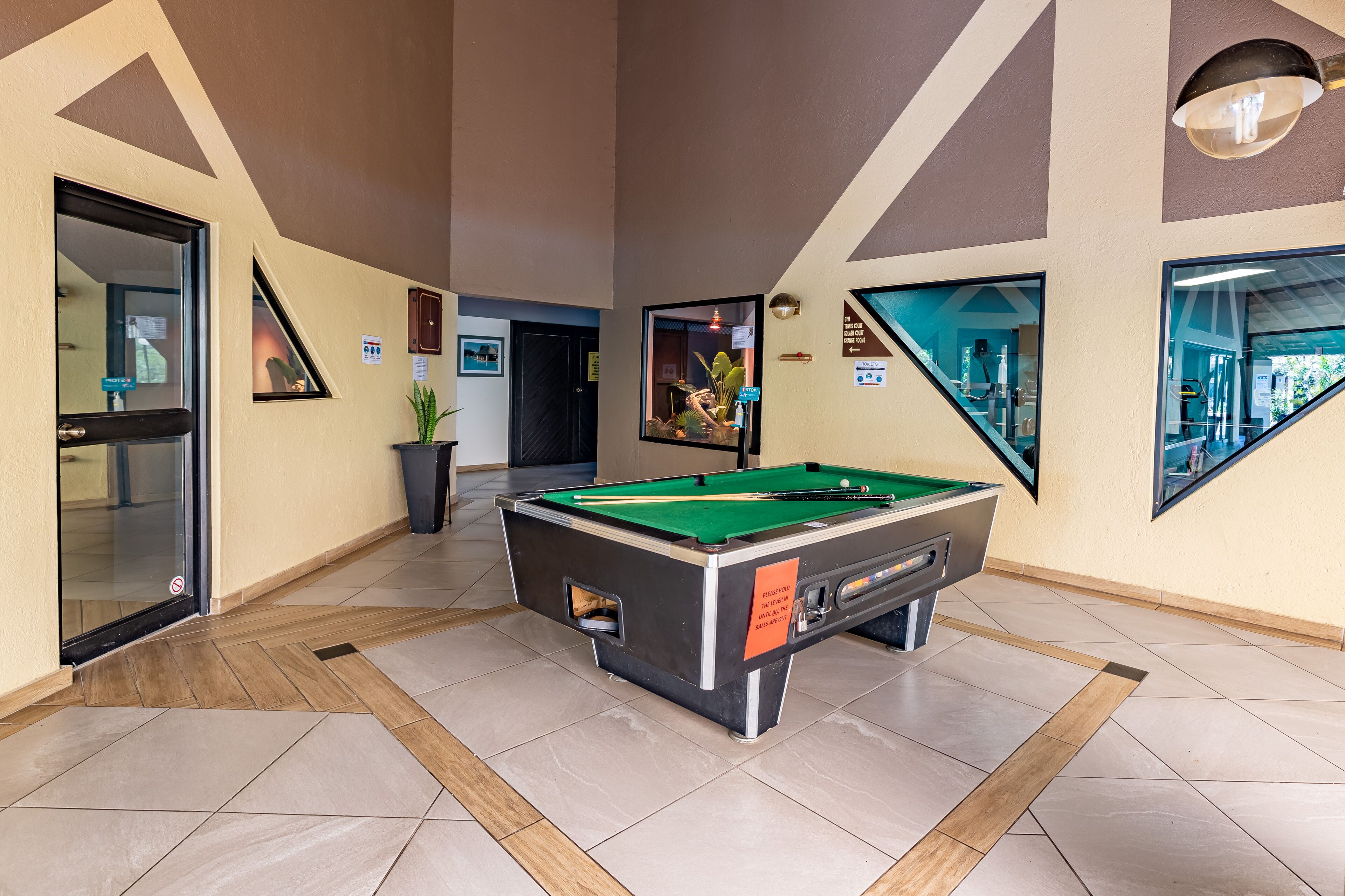 Uma mesa de bilhar em área interna ampla, com teto alto e elementos de design moderno.