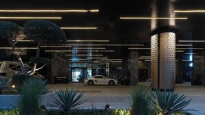 Um edifício moderno com um carro branco estacionado na frente, com iluminação horizontal e padrões geométricos.