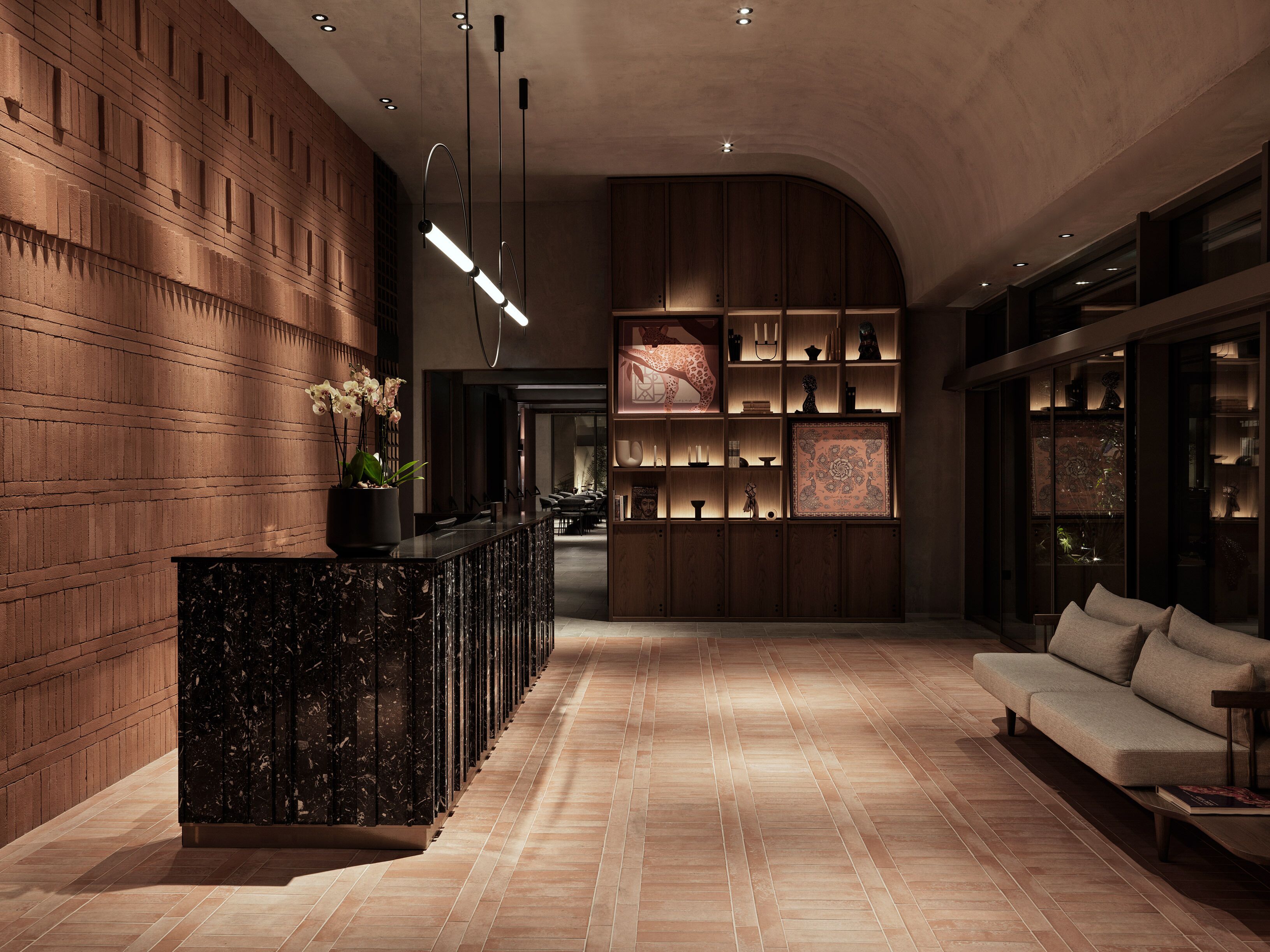 Um hall moderno com uma receção de mármore, estantes de madeira com objetos decorativos e um sofá.
