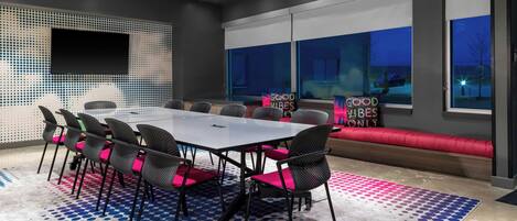 Uma sala de conferências moderna com uma mesa grande, cadeiras e um sofá.