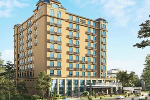 Hotel com vários andares, fachada bege, inúmeras varandas e design arquitetônico moderno.