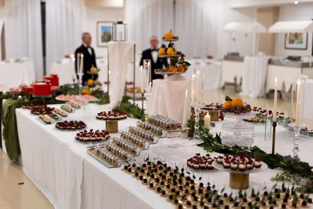 Mesa de buffet com diversos alimentos e um arrumeiro de sobremesas.