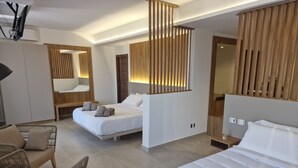 Quarto de hotel moderno com uma cama grande, um sofá, uma cadeira e um painel de madeira.