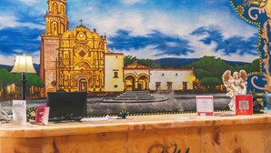 Bancada de recepção com um mural de uma igreja, uma luminária e uma estátua.