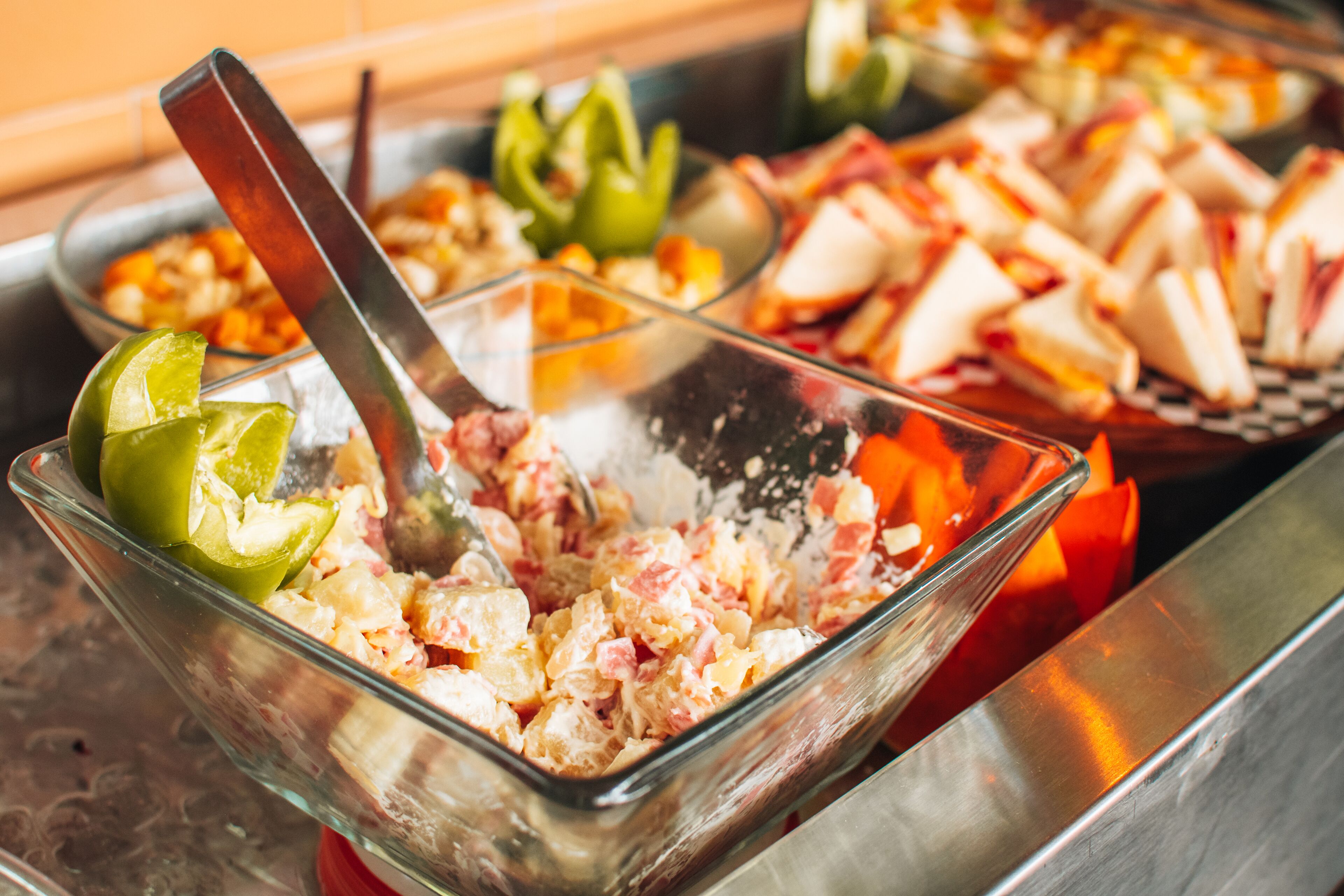 Buffet com diversos pratos, incluindo salada, frutas e sanduíches.