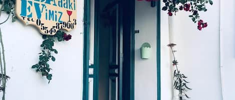 Edifício branco com porta verde e placa com a inscrição 'ADA daki EViMIZ'.