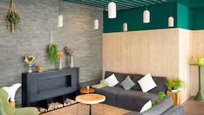 Uma sala de estar moderna com um sofá cinza, um móvel de entretenimento preto e uma parede verde de destaque.