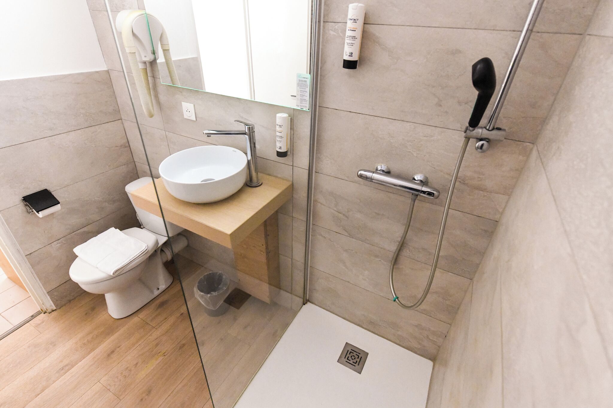 Um banheiro moderno com box de vidro, pia branca e vaso sanitário.