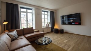 Uma sala de estar moderna com sofá de couro, mesa de centro e televisão de tela plana na parede.