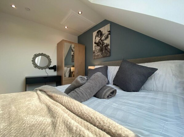 Quarto com uma cama, mesa de cabeceira, espelho e um quadro na parede.