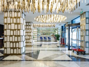 Um hall de hotel com balcão de check-in, área de bar e balcão de recepção.