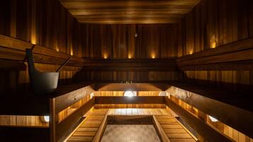 Uma sauna com bancos de madeira e piso aquecido central, iluminada por pequenas luzes.