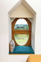 Quarto com janela embutida e vista para uma paisagem verde.